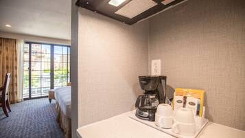 Quarto de hotel com cama, cafeteira, xícaras e bandeja com cardápio.