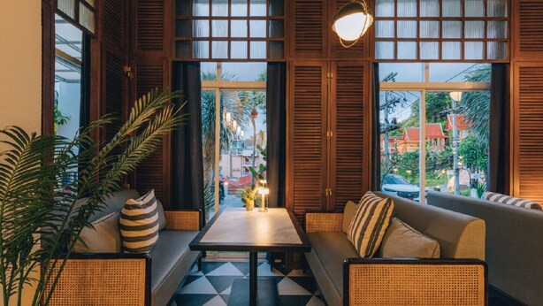 Quarto com sofá, mesa e vista através de grandes janelas.