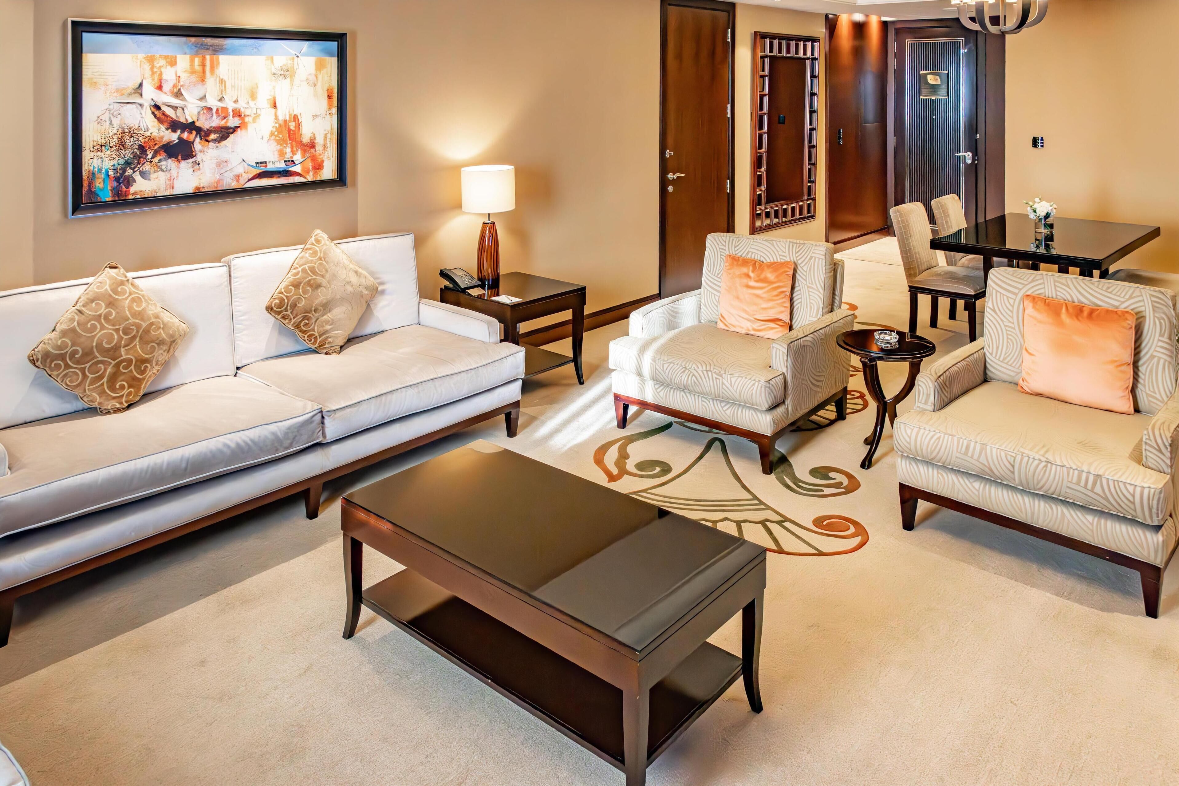 Uma sala de estar moderna com sofá, poltronas, mesa de centro e mesa de jantar.