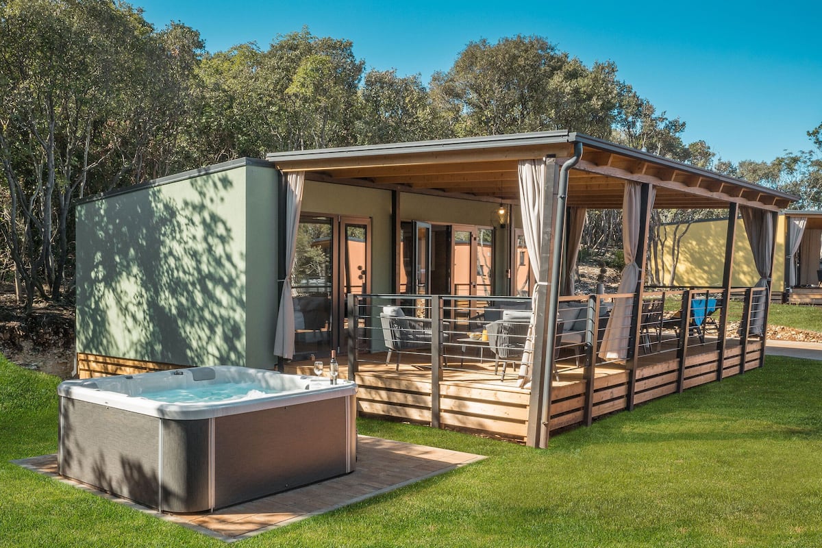 Uma área de spa com hidromassagem, deck de madeira e área de estar externa.