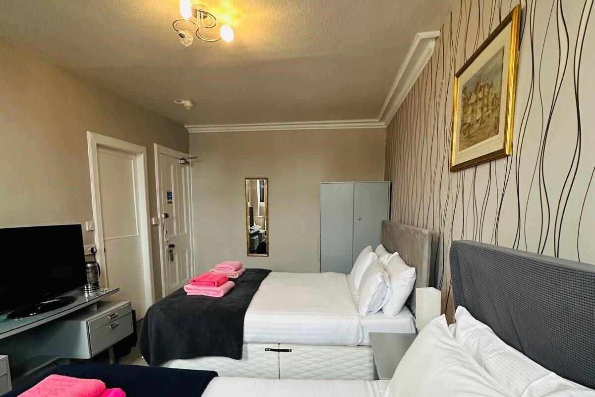 Quarto de hotel com duas camas, televisão, escrivaninha e espelho.