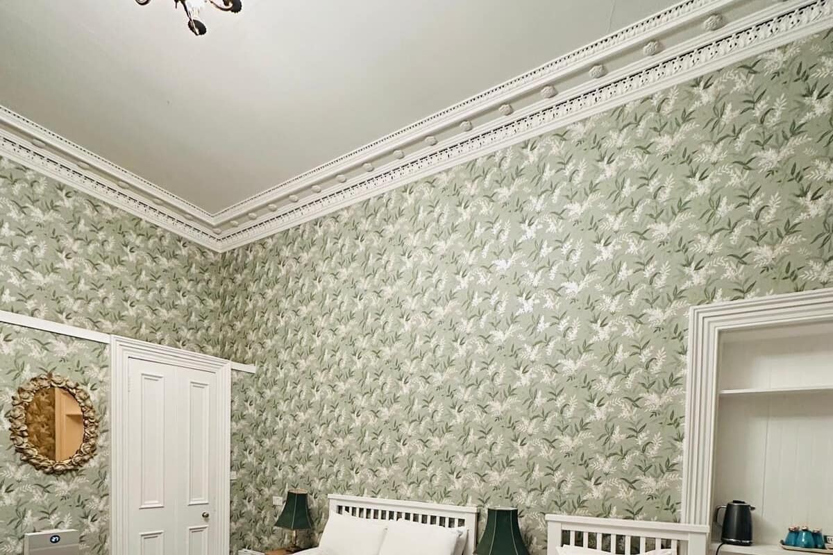 Quarto com duas camas, um espelho, um guarda-roupa e um candelabro.