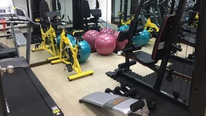 Uma academia com diversos equipamentos de exercício, incluindo esteiras, aparelhos de musculação e bolas de ginástica.