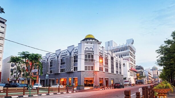 Um edifício moderno com uma cúpula amarela destacada, uma joalheria no andar térreo e uma rua com carros e uma faixa de pedestres.