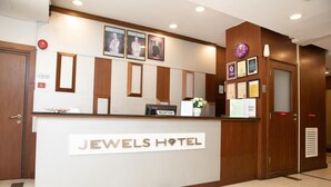 Bancada de recepção no Jewels Hotel, com uma placa, quadros emoldurados e certificados na parede.