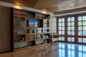 Quarto espaçoso com uma grande estante de madeira, uma TV de tela plana e uma ampla porta de vidro com vista para o exterior.