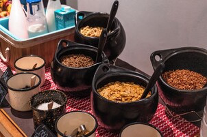 Diversos vasos pretos com diferentes conteúdos sobre uma mesa com toalha quadriculada vermelha e branca.