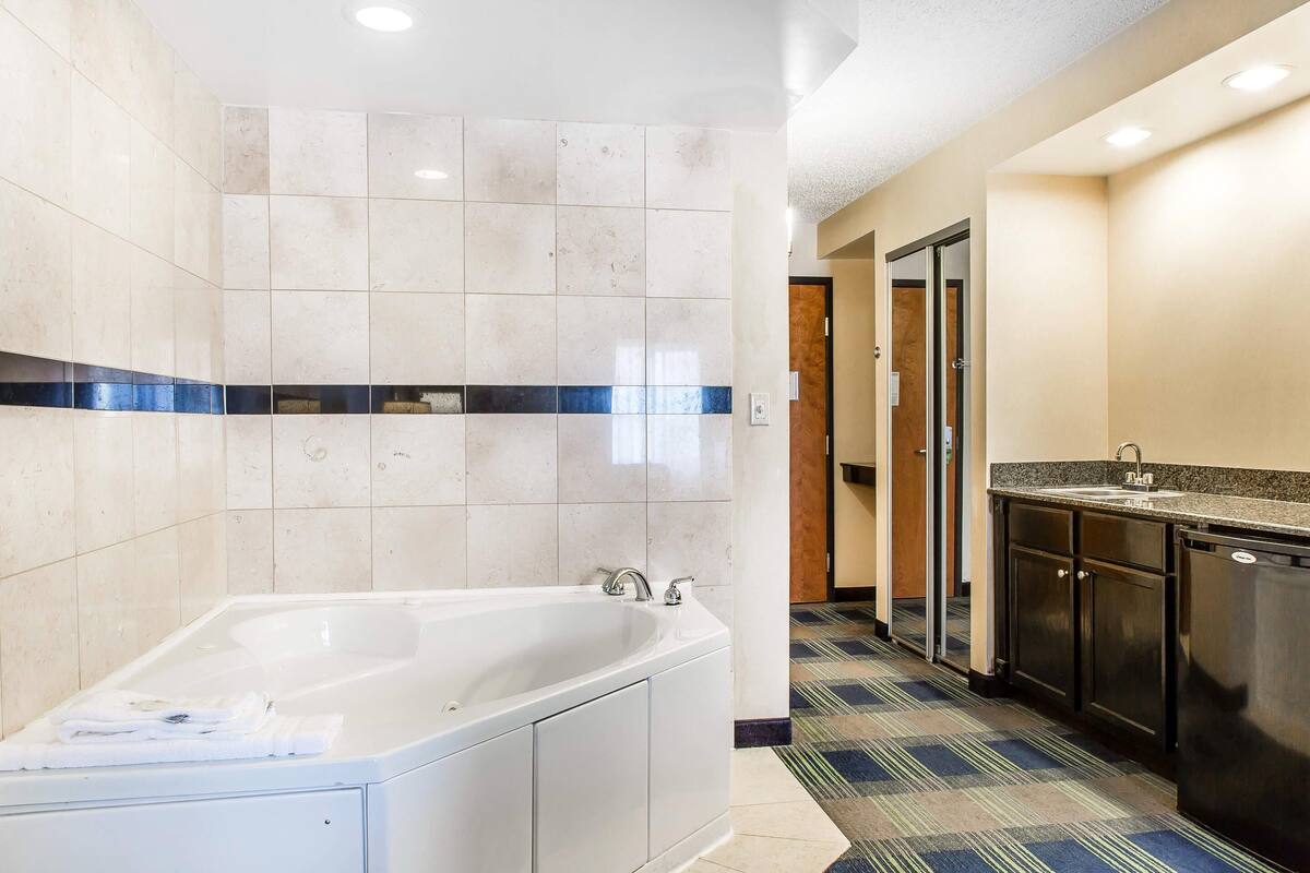 Um banheiro moderno com uma banheira grande, pia e piso revestido de azulejos.