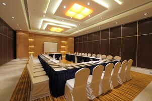 Uma sala de conferências com uma mesa comprida, cadeiras e uma tela de projetor.