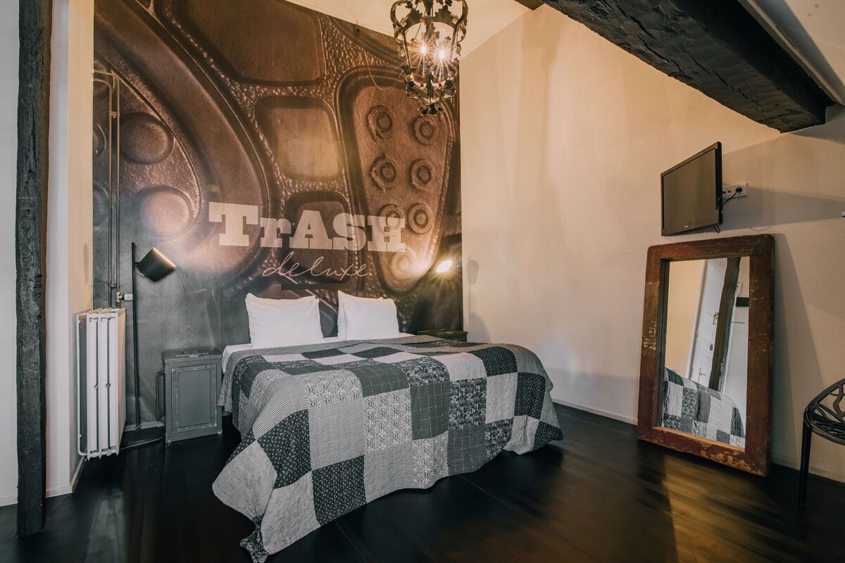 Quarto com cama grande, lustre, radiador e espelho.
