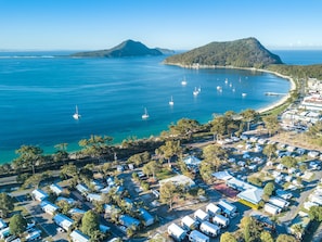Vista aérea de uma área costeira com vários trailers, uma praia e algumas embarcações na água.