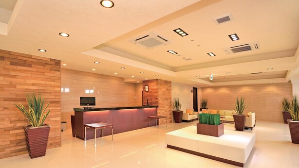 Um lobby de hotel moderno com balcão de recepção, área de estar e plantas em vasos.