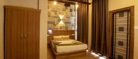 Quarto com cama de madeira, guarda-roupa, parede de pedra e porta com padrão de grade.