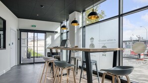 Um interior moderno com uma mesa de madeira, luminárias pendentes douradas e pretas, e banquetas de metal.