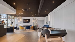 Uma área de estar moderna com mesa de pebolim, assentos e bar com prateleiras.