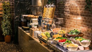 Buffet com diversas opções de comida, incluindo saladas, frutas e cereais.