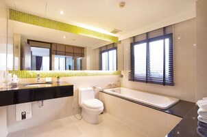 Uma casa de banho moderna com bancada preta, sanita branca, banheira e um espelho grande.