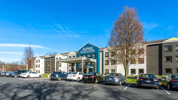 Um hotel com uma placa grande indicando "ASPIRE HOTEL & SUITES", com um estacionamento em frente.