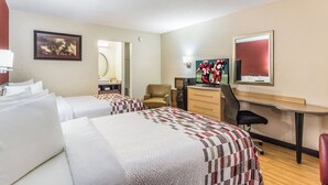 Quarto de hotel com duas camas, uma escrivaninha, uma cadeira, uma televisão e um espelho.