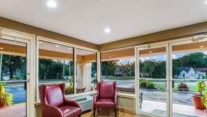 Quarto com duas poltronas de couro, uma janela grande e vista para um bairro residencial.