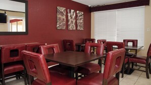 Uma área de refeições com bancos estofados em vermelho e mesa de madeira escura.