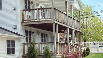 Uma casa de dois andares com varanda, cerca branca de piquete e gramado bem cuidado.