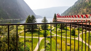 Um hotel com fachada vermelha e branca, localizado à beira de um lago com montanhas ao fundo.