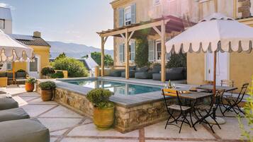 Área da piscina com mobiliário exterior, pérgola e vista para montanhas.