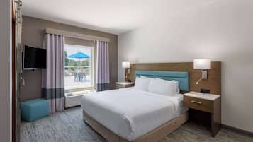 Quarto de hotel com uma cama grande, duas mesas de cabeceira, uma TV de tela plana, janela com cortinas e vista para o exterior.