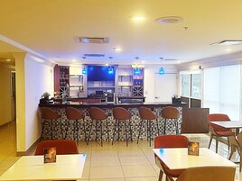 Restaurante com área de bar, diversas opções de assento e parede estampada.