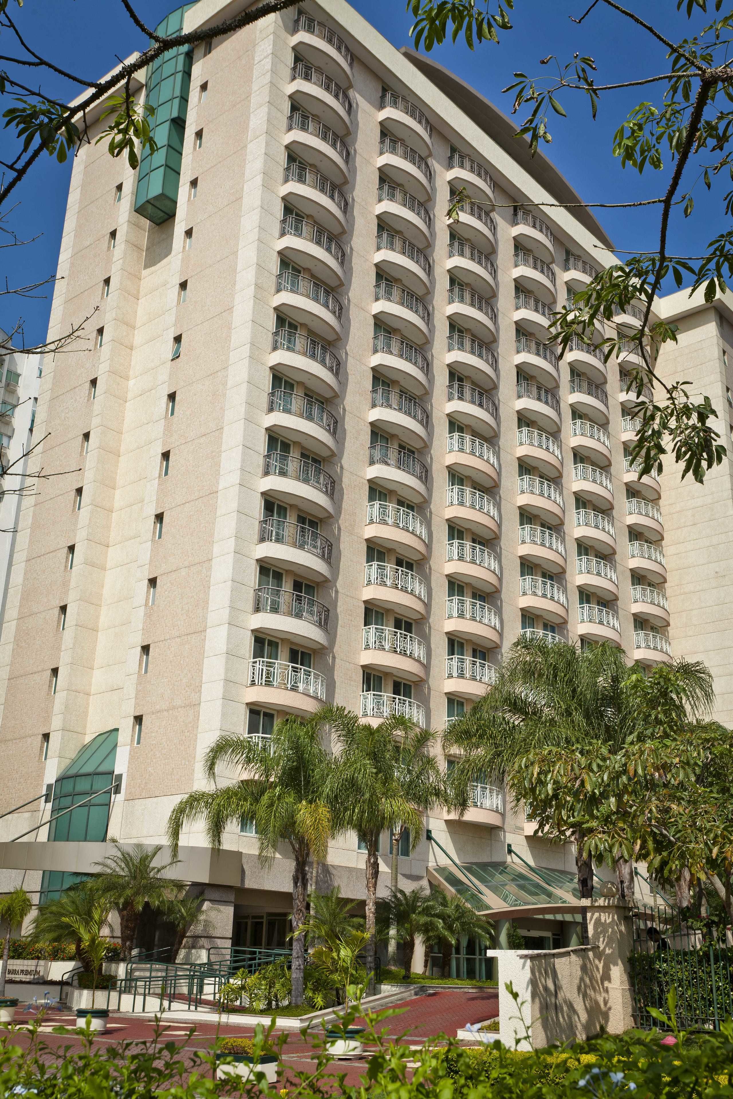 Um hotel de vários andares com fachada bege, várias varandas e toldo verde.