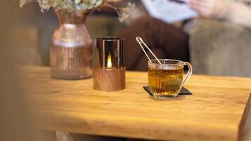 Uma mesa de madeira com um vaso de flores, uma vela e uma xícara de chá.