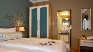 Quarto de hotel com cama, guarda-roupa, casa de banho com lavatório e espelho.