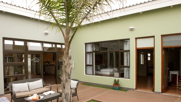 Um hotel moderno com área de pátio, incluindo um sofá, uma mesa de centro e um vaso de planta.