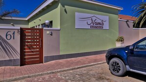 Uma pousada com uma placa indicando 'Namib GUESTHOUSE' e o número '61' na parede.