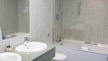 Uma casa de banho com duas pias, sanita e banheira.