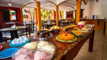 Um buffet com diversos tipos de comida e um bolo sobre uma mesa de madeira.