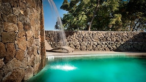 Mural de pedra com um elemento de água e piscina.