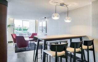 Uma sala de jantar moderna com uma mesa de madeira e cadeiras pretas, uma cadeira vermelha e uma janela grande com vista para o exterior.