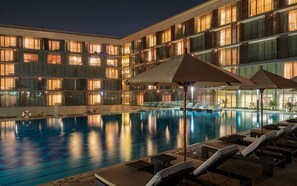 Um hotel com piscina, espreguiçadeiras e guarda-sóis.