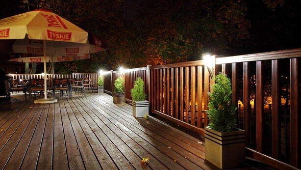 Um deck de madeira com área de estar externa e um toldo identificado como 'TYSKIE'.