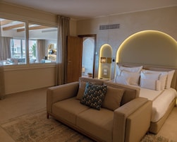 Quarto de hotel com cama, sofá, janela grande e vista da cidade.