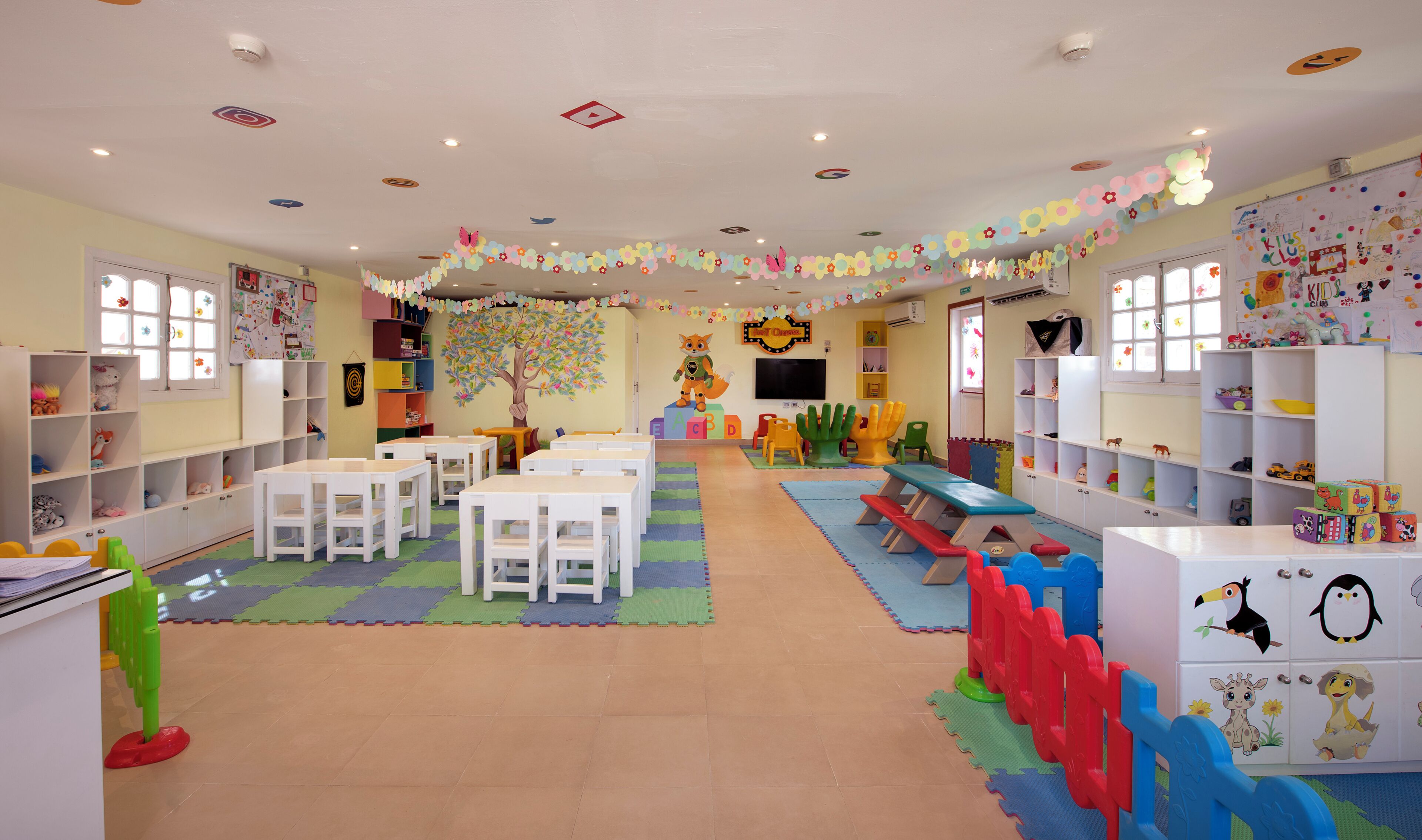 Uma sala de brinquedos infantis com mesas, cadeiras e brinquedos educativos.