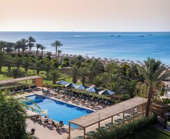 Um resort com piscina, espreguiçadeiras, guarda-sóis e vista para o mar.