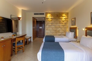 Quarto de hotel com uma cama, uma escrivaninha, uma cadeira e uma televisão.
