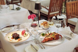 Uma mesa de jantar posta com pratos de comida, copos de vinho e talheres.