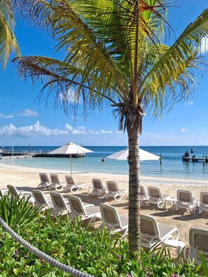 Na praia, praia de areia branca, espreguiçadeiras, guarda-sóis de praia 