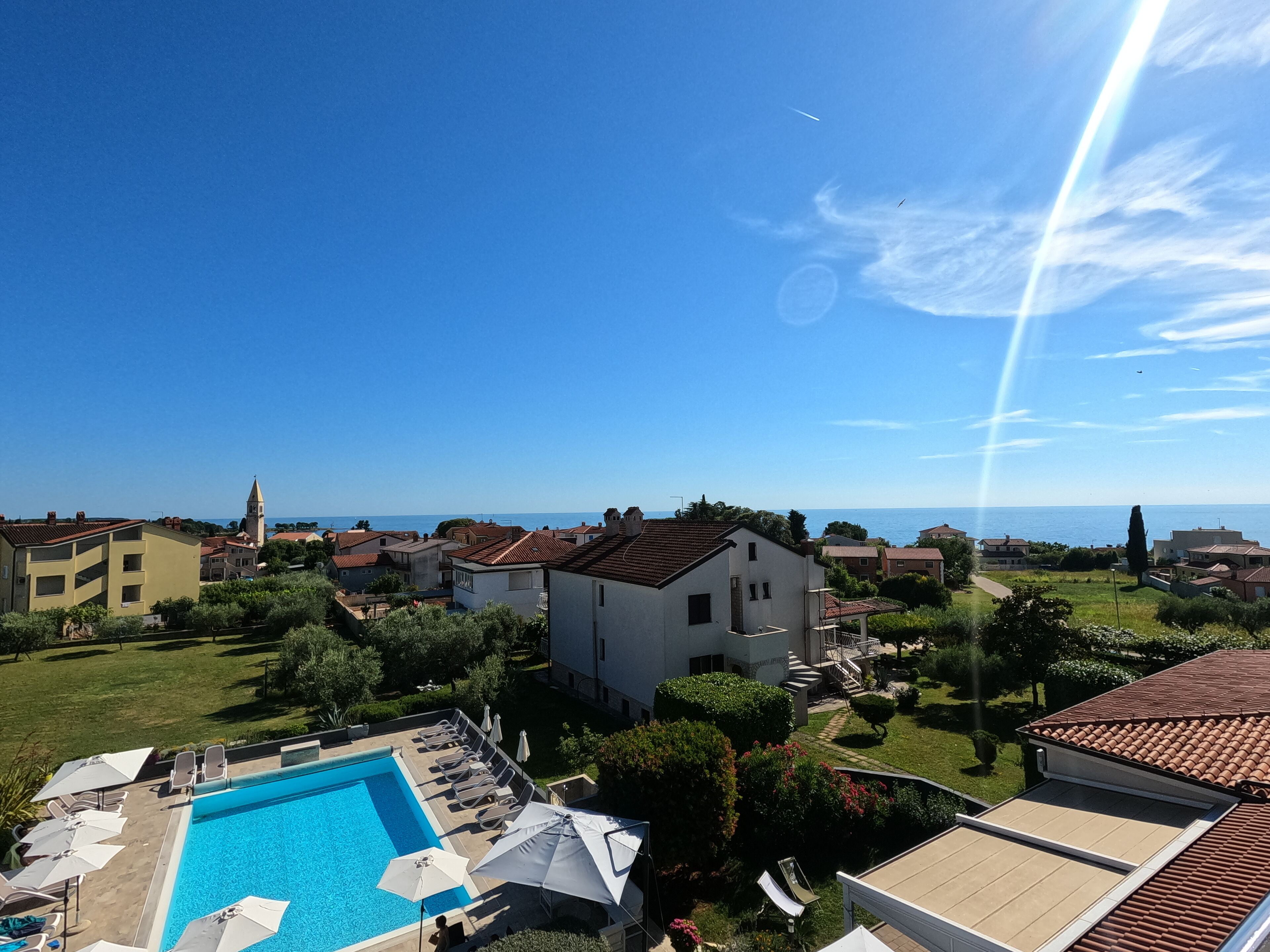 Zona residencial com piscina, cadeiras de lounge e vista para o mar.