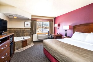Quarto de hotel com cama, secretária, cadeira, televisão, banheiro com pia e banheira, e janela com vista para o exterior.