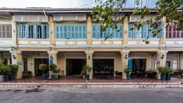 Fileira de edifícios em estilo colonial, com várias varandas e um alpendre com área de estar ao ar livre.